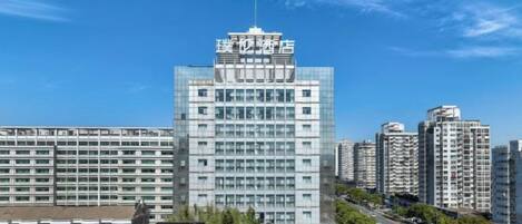 Um hotel imponente com vários andares, entrada destacada e vista ampla da paisagem urbana ao redor.