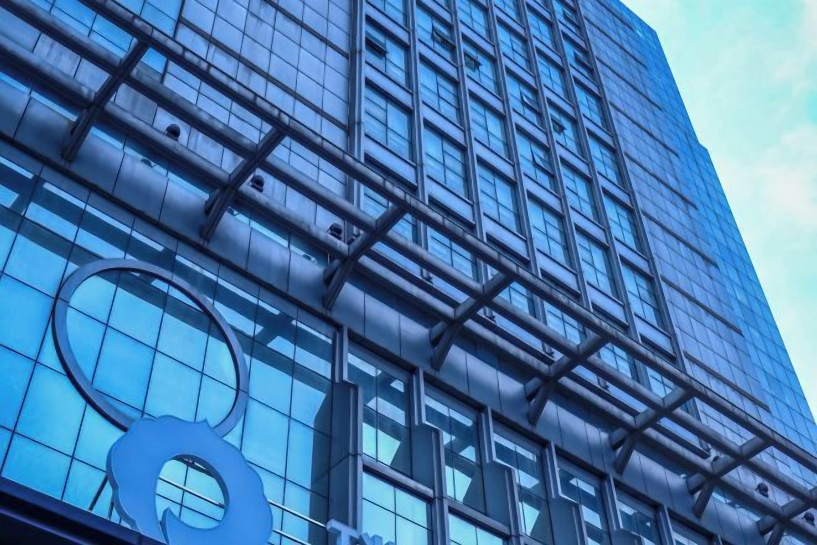 Um edifício moderno com fachada de vidro e um logotipo circular destacado.