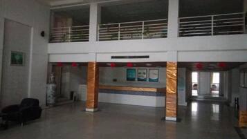 Um hall amplo com balcão de recepção, área de estar e varanda.