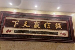 Uma placa emoldurada com caracteres chineses e uma fileira de controles remotos abaixo.