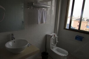 Casa de banho com lavatório branco, sanita e suporte para toalhas.