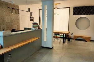 Uma área de recepção com balcão, assentos e uma janela ampla.