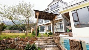 Uma casa moderna de dois andares com um caminho de pedra que leva a uma pérgula de madeira.