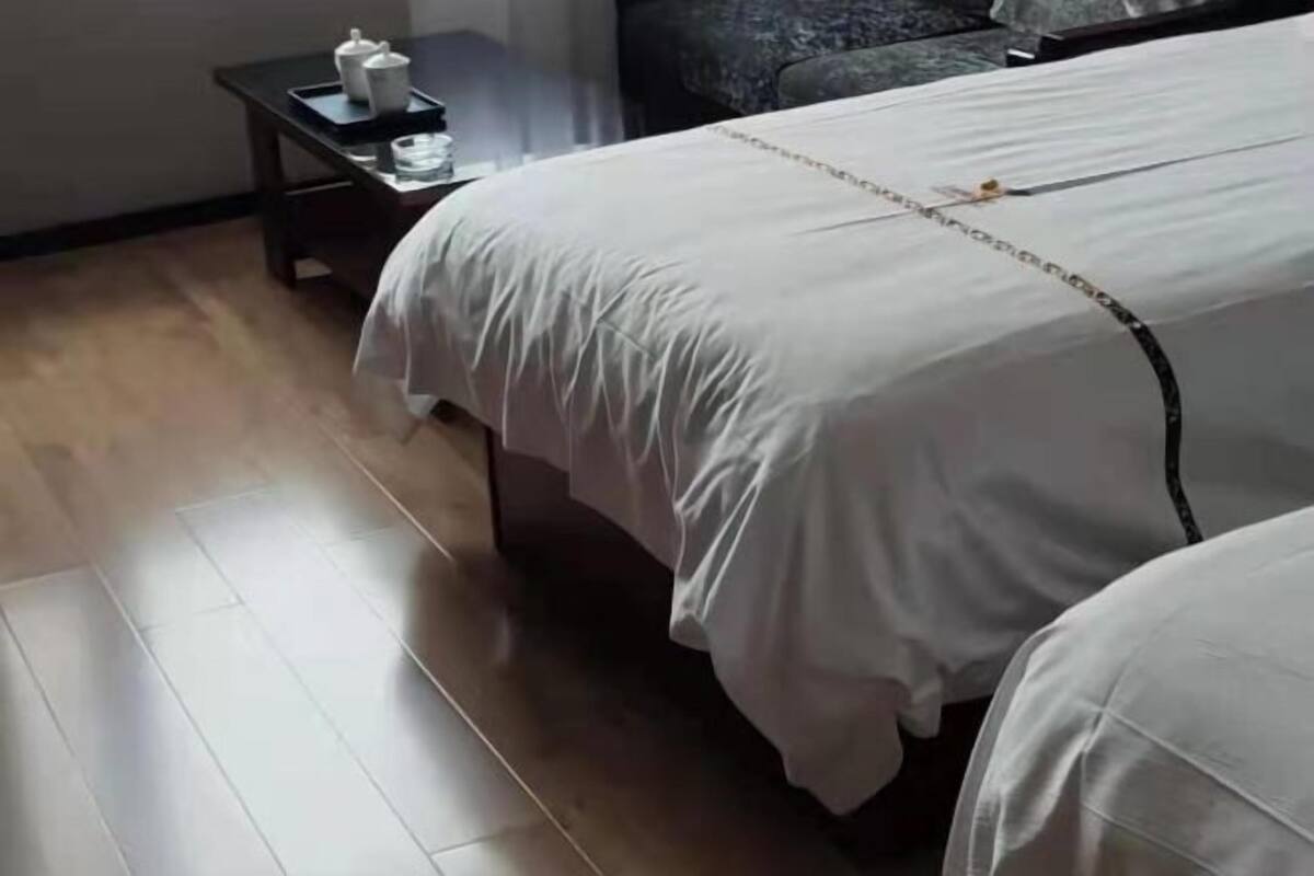 Quarto de hotel com duas camas, uma mesinha com bandeja e uma mesa de cabeceira.