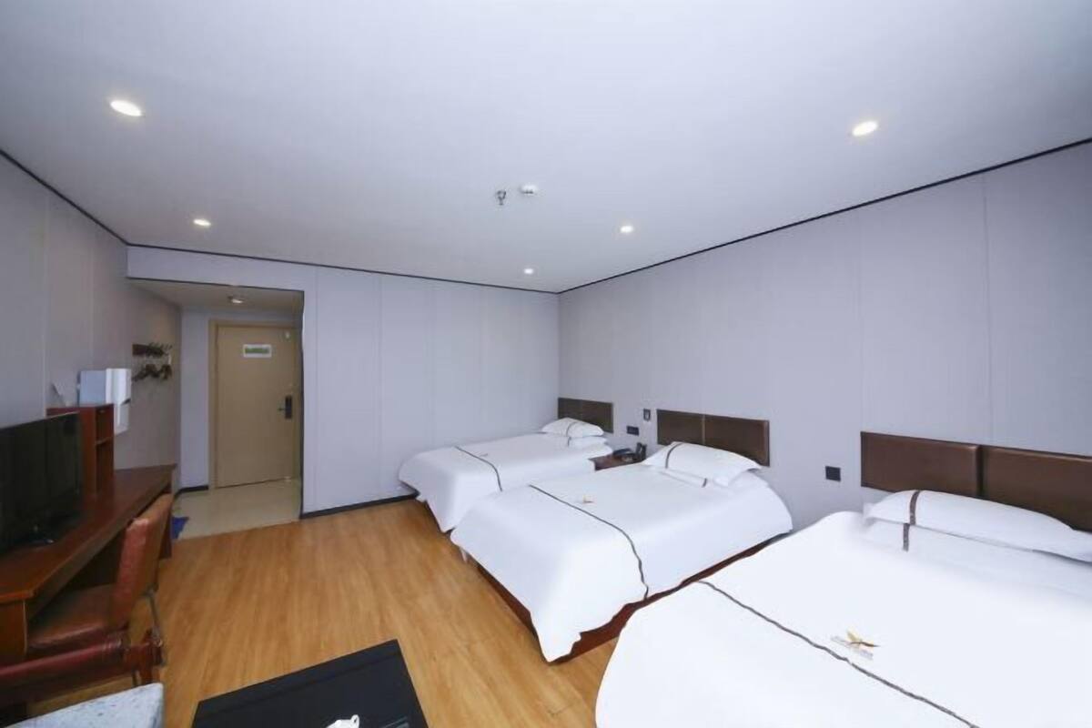 Quarto de hotel com duas camas, televisão e chão de madeira.