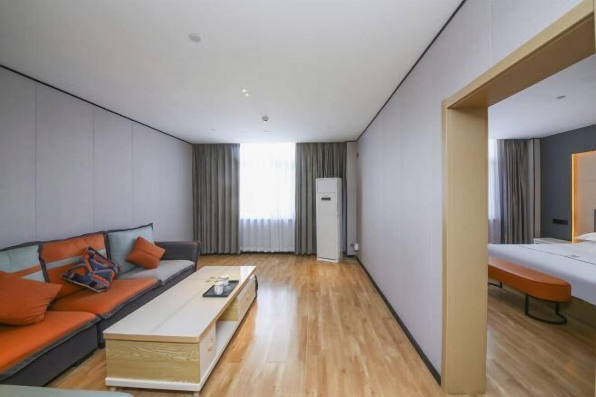 Quarto de hotel moderno com sofá, mesa de centro, cama e escrivaninha.