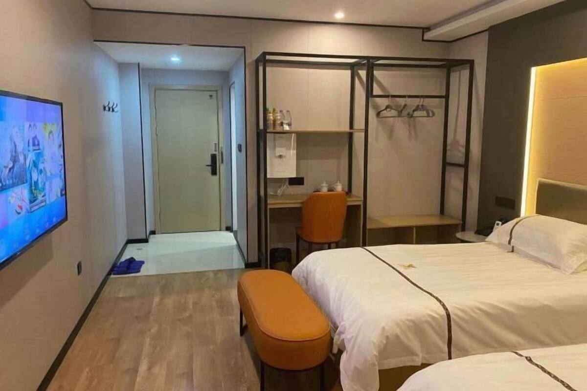 Quarto de hotel com duas camas, uma escrivaninha, uma cadeira e um guarda-roupa.