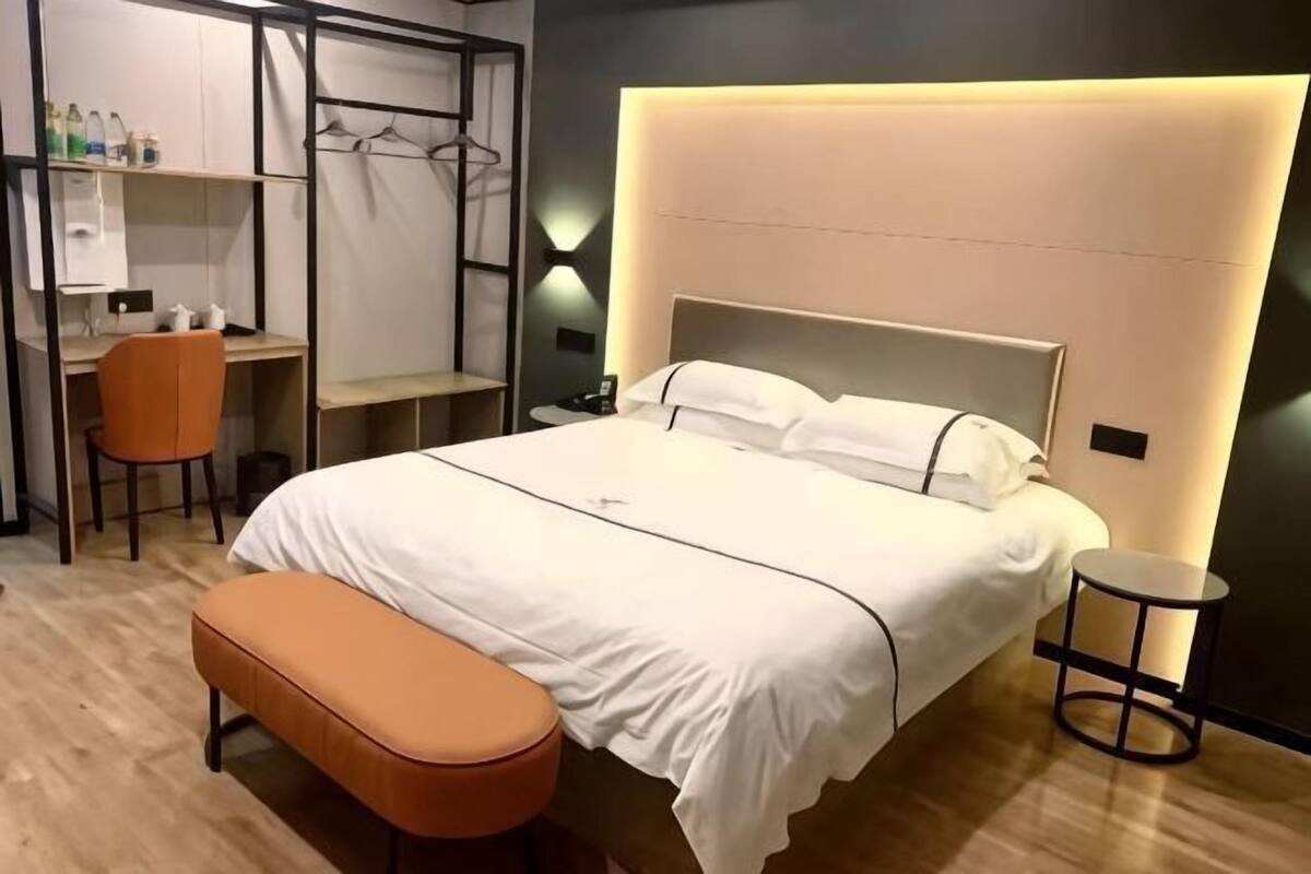Quarto de hotel moderno com uma cama grande, uma escrivaninha e uma cadeira.