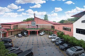 Um edifício com telhado vermelho, um estacionamento com vários carros e um céu claro.