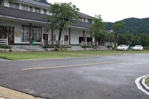 Um edifício com arquitetura tradicional, uma rua pavimentada em frente e carros estacionados.