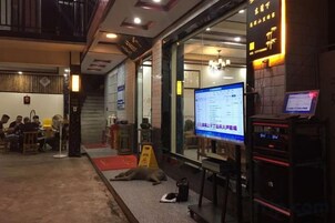 Um hall de hotel com área de estar, um computador em uma mesa e um cão deitado no chão.