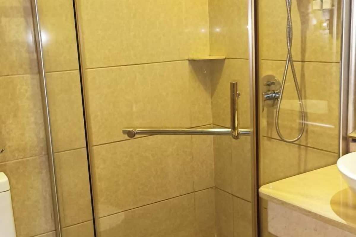 Área de chuveiro com porta de vidro, porta-toalhas e chuveiro.