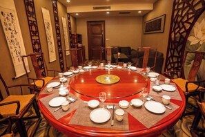 Mesa de jantar redonda com cadeiras, posta para refeição, em um quarto com decoração tradicional.