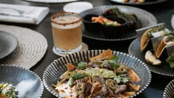 Uma mesa de jantar com diversos pratos, incluindo um prato de nachos, um copo de bebida e outros alimentos.