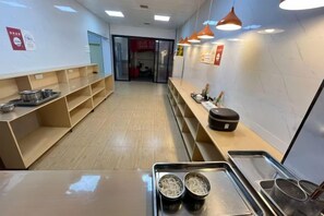 Cozinha equipada com eletrodomésticos de aço inoxidável, prateleiras de madeira e bancada com utensílios de cozinha.