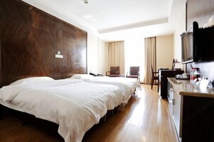 Quarto de hotel com duas camas, uma escrivaninha, uma televisão e vista para o exterior.