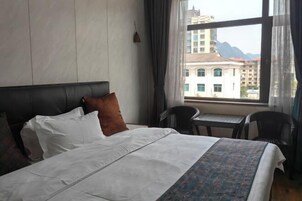Quarto de hotel com uma cama, uma pequena mesa e uma cadeira.