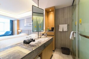 Quarto de hotel com cama, banheiro com pia, espelho e chuveiro.