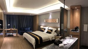 Quarto de hotel moderno com uma cama grande, mesa de cabeceira e escrivaninha com cadeira.