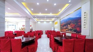 Uma sala de conferências com mesas e cadeiras revestidas de vermelho, uma pintura grande na parede e um teto com iluminação embutida.