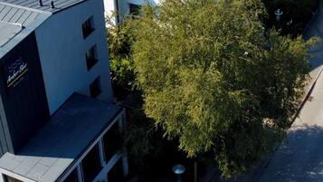 Um edifício com telhado plano e uma grande árvore à frente.