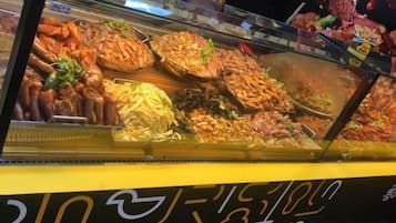 Vitrine de vidro com diversos alimentos, incluindo salsichas, carnes e legumes.