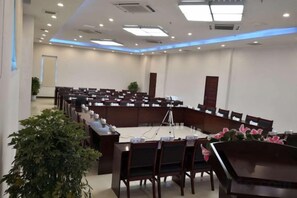 Sala de conferências com uma longa mesa, cadeiras e um púlpito.
