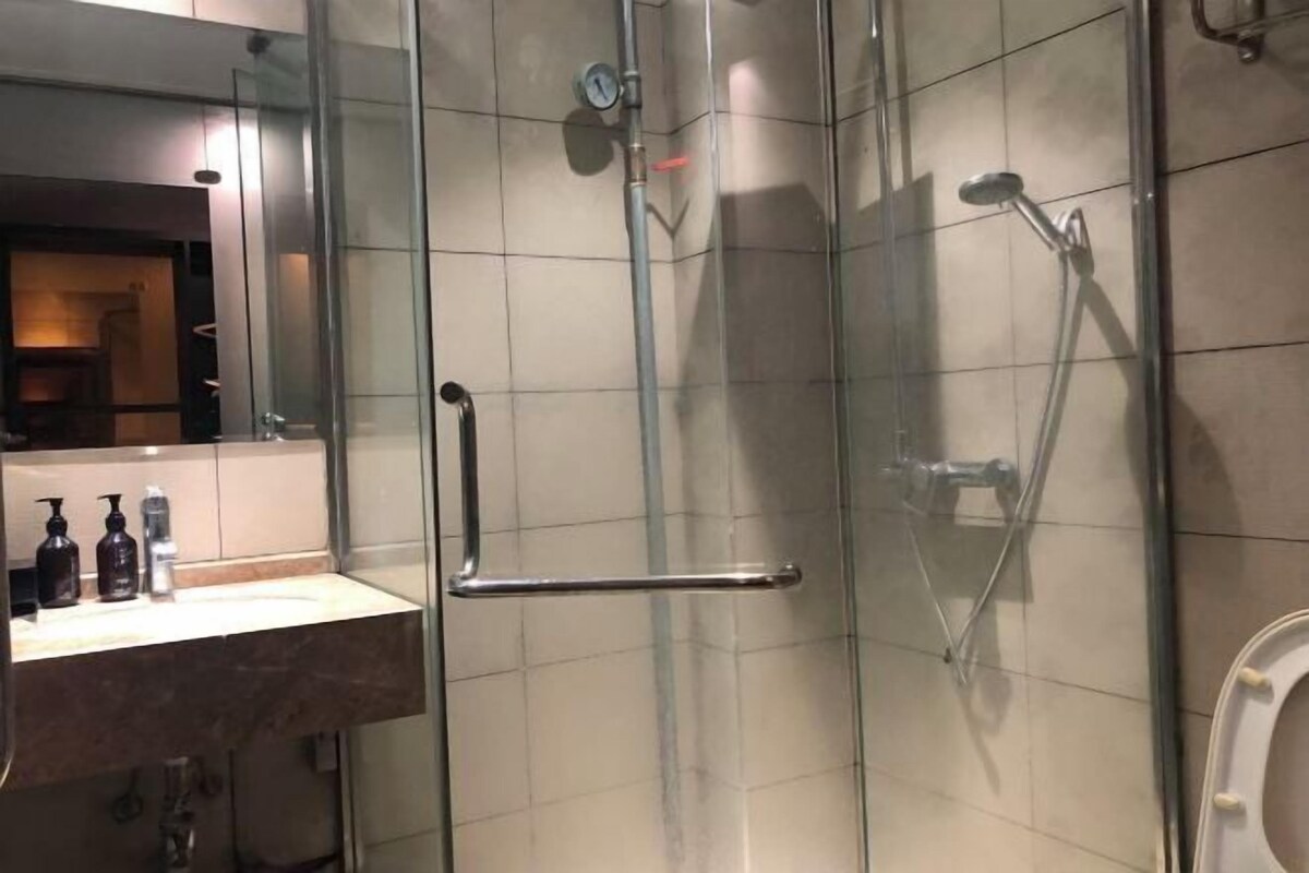 Um banheiro moderno com chuveiro envidraçado, toucador com espelho e vaso sanitário.