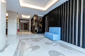 Um hall moderno com um sofá azul, piso estampado e parede com linhas verticais.