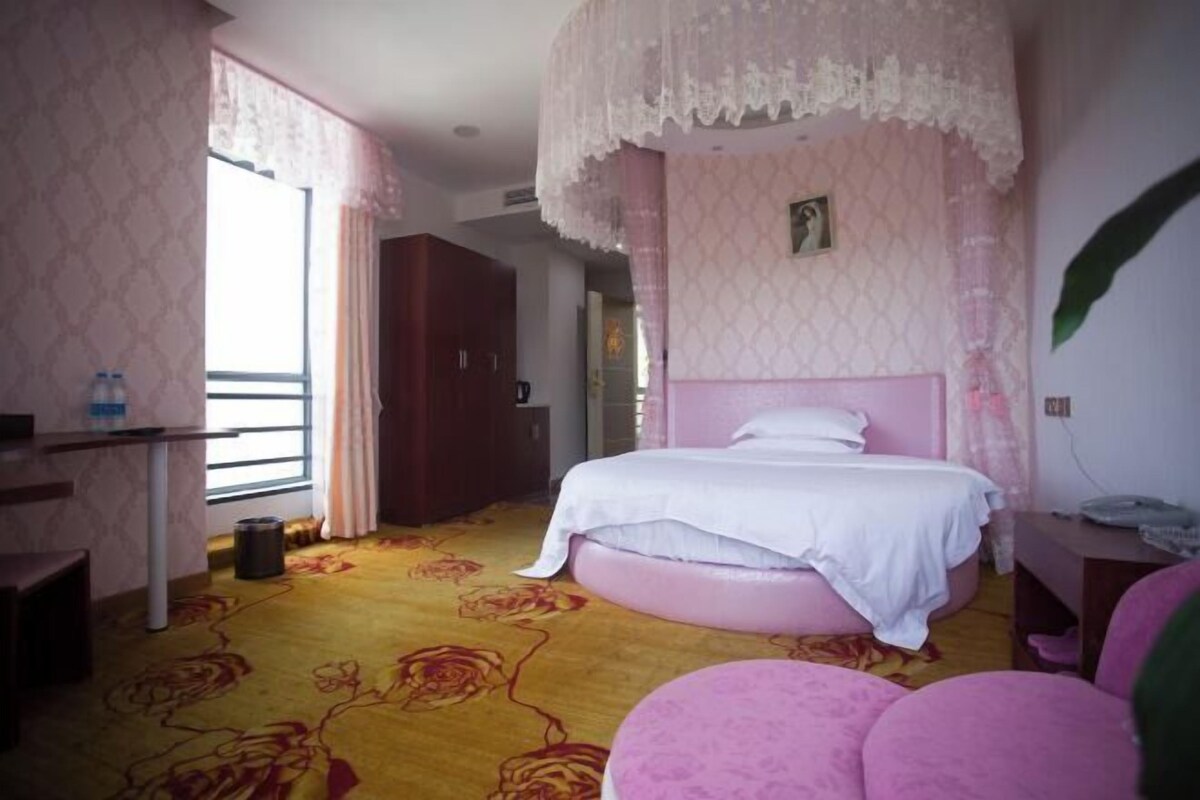 Quarto com cama, escrivaninha, cadeira e janela com cortinas.