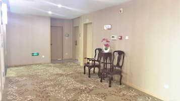 Corredor de hotel com piso em carpete, balcão de recepção e porta com a inscrição '1011'.