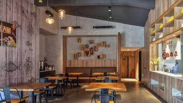 Interior de restaurante com mesas e cadeiras de madeira, área de bar e decorações nas paredes.