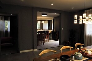 Uma sala de jantar moderna com mesa de madeira, cadeiras e um lustre.
