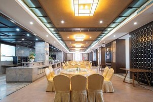 Uma sala de conferências ampla com uma mesa redonda e cadeiras, área de bar e adega.