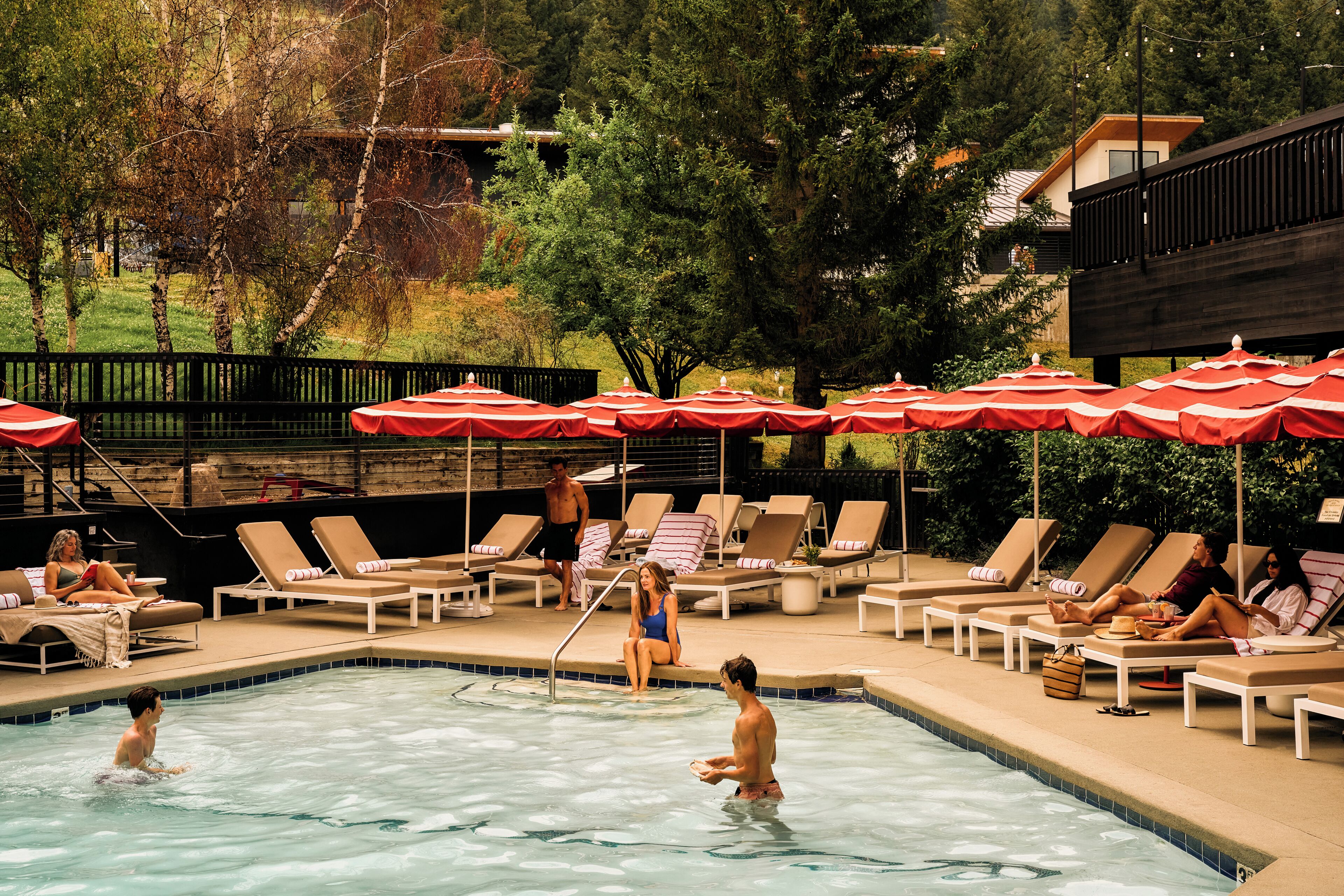 Área de piscina com espreguiçadeiras e guarda-sóis.