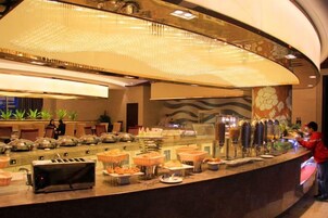 Uma área de buffet com diversos pontos de comida, uma máquina de café e um atendente.