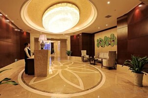 Um saguão de hotel com balcão de recepção, área de estar e um grande design circular no chão.