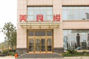 Um edifício com uma entrada ampla, uma placa com caracteres chineses e uma escadaria que leva à porta.