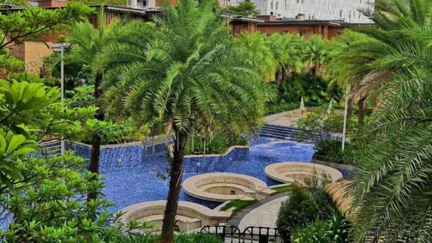 Resort com piscina central rodeada por palmeiras e um caminho de pedra.