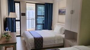 Quarto de hotel com duas camas, uma escrivaninha com abajur, um vaso de flores e vista através de uma porta de vidro.