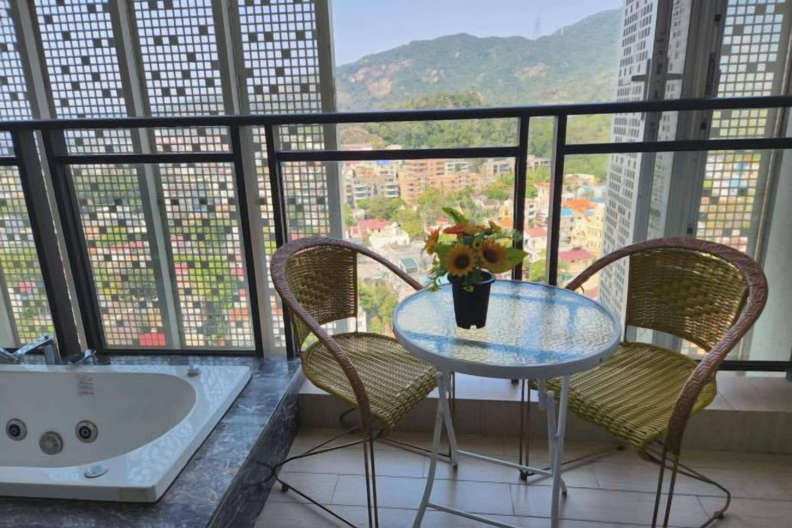 Uma varanda com hidromassagem, cadeiras de vime e uma mesa com um vaso de flores.