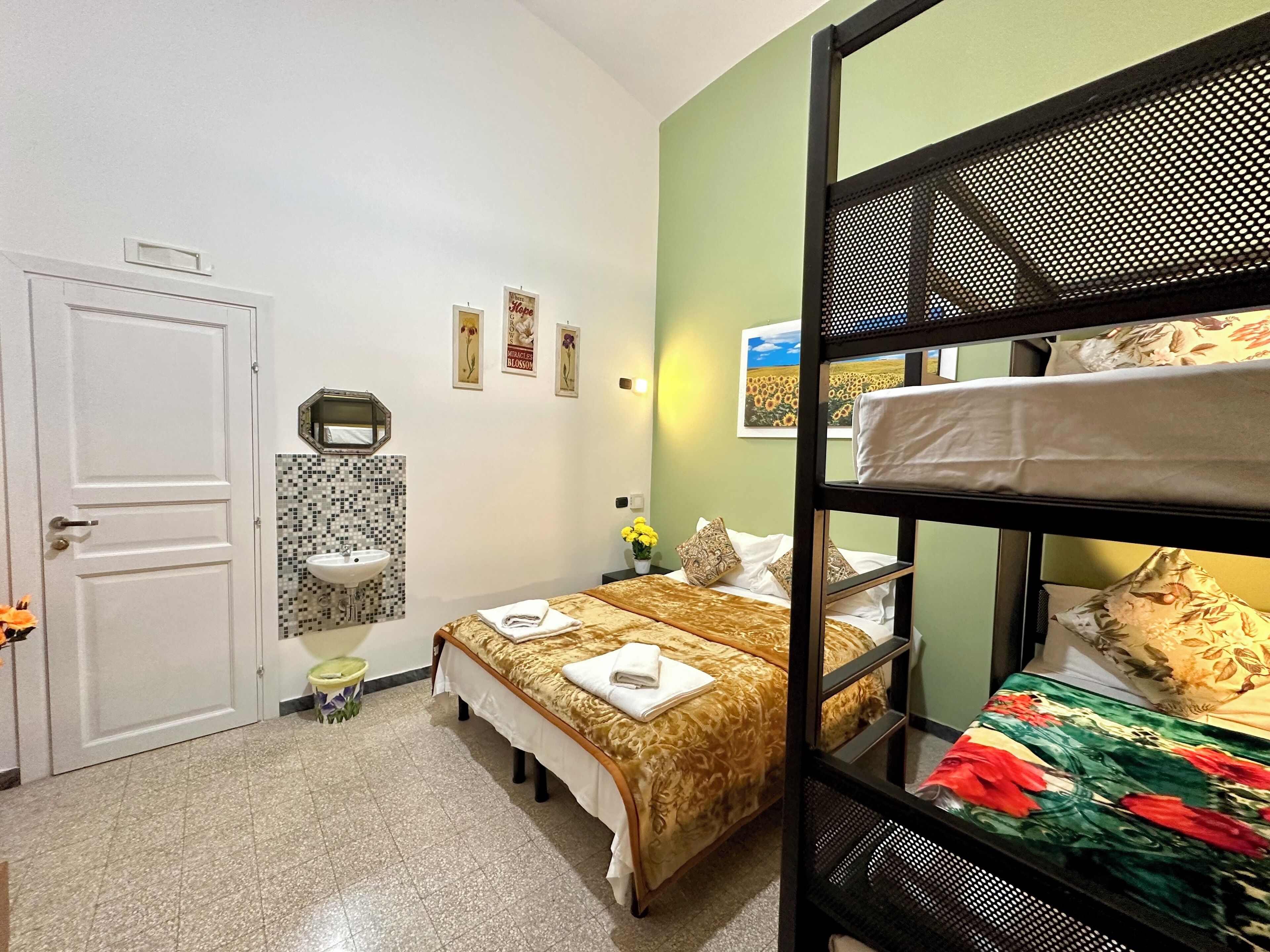 Quarto com beliche, uma cama de solteiro, pia e porta.