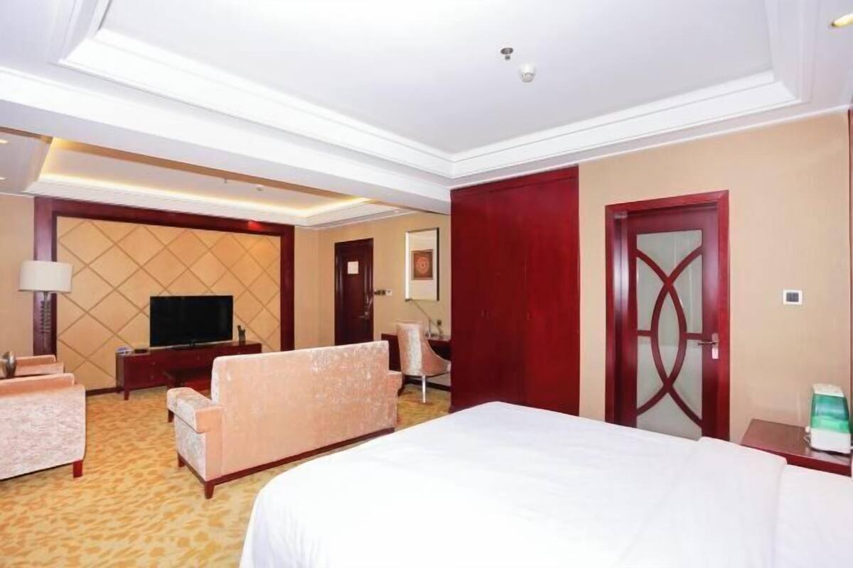 Quarto de hotel com cama, televisão, escrivaninha e cadeira.