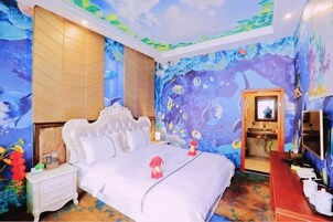 Quarto com cama grande, mesa de cabeceira, cômoda e um mural na parede.