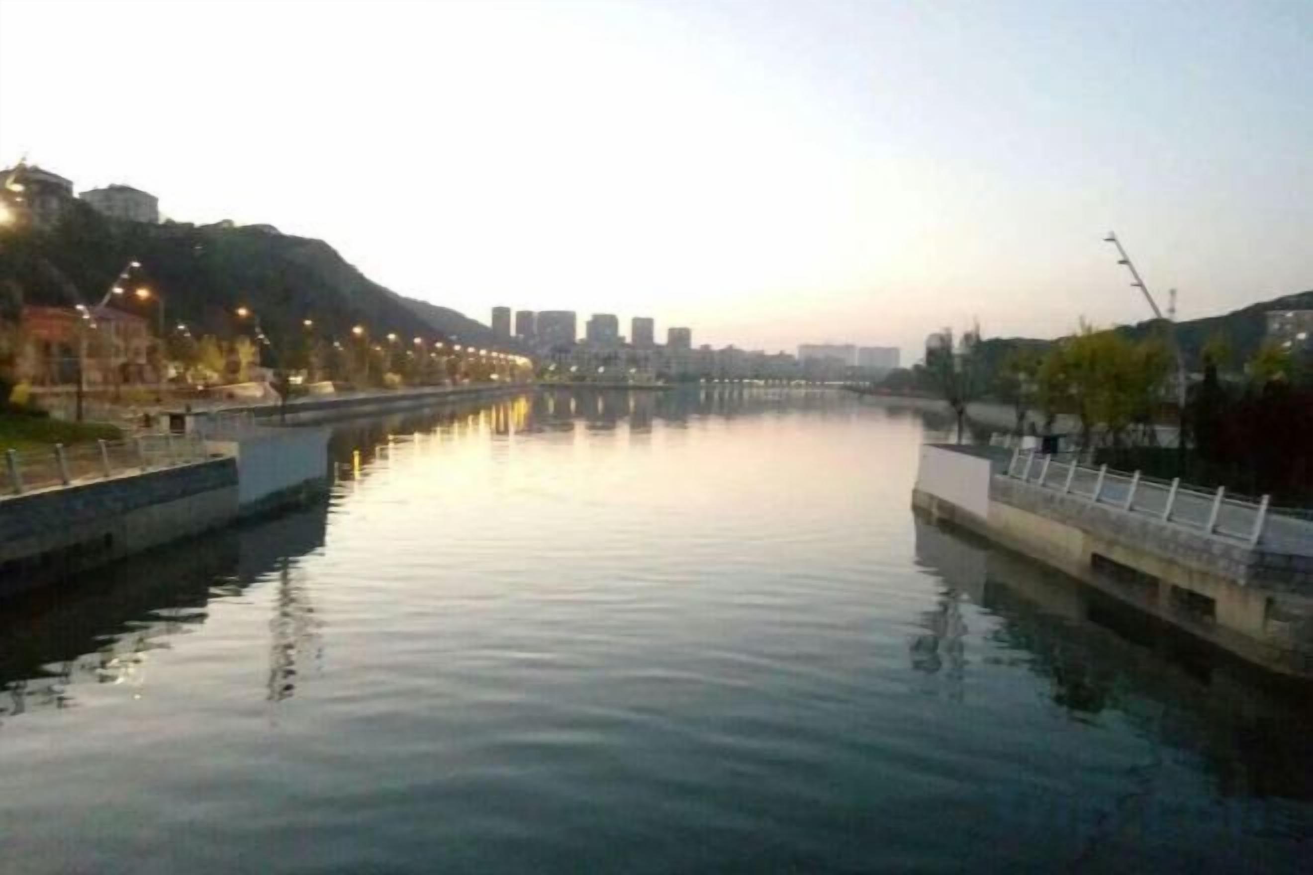 Um rio calmo com uma ponte e edifícios ao fundo.
