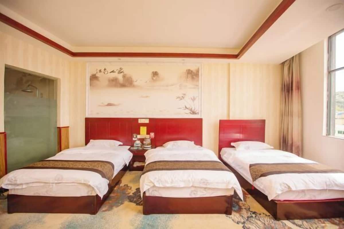 Quarto de hotel com duas camas, um quadro grande na parede e uma janela com cortinas.