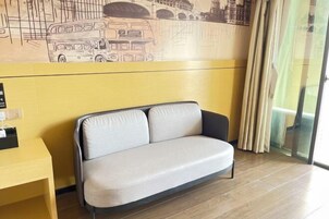 Quarto com sofá, mesa amarela e um mural de um ônibus na parede.