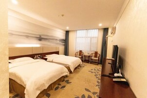 Quarto de hotel com duas camas, uma mesa com telefone e uma televisão.