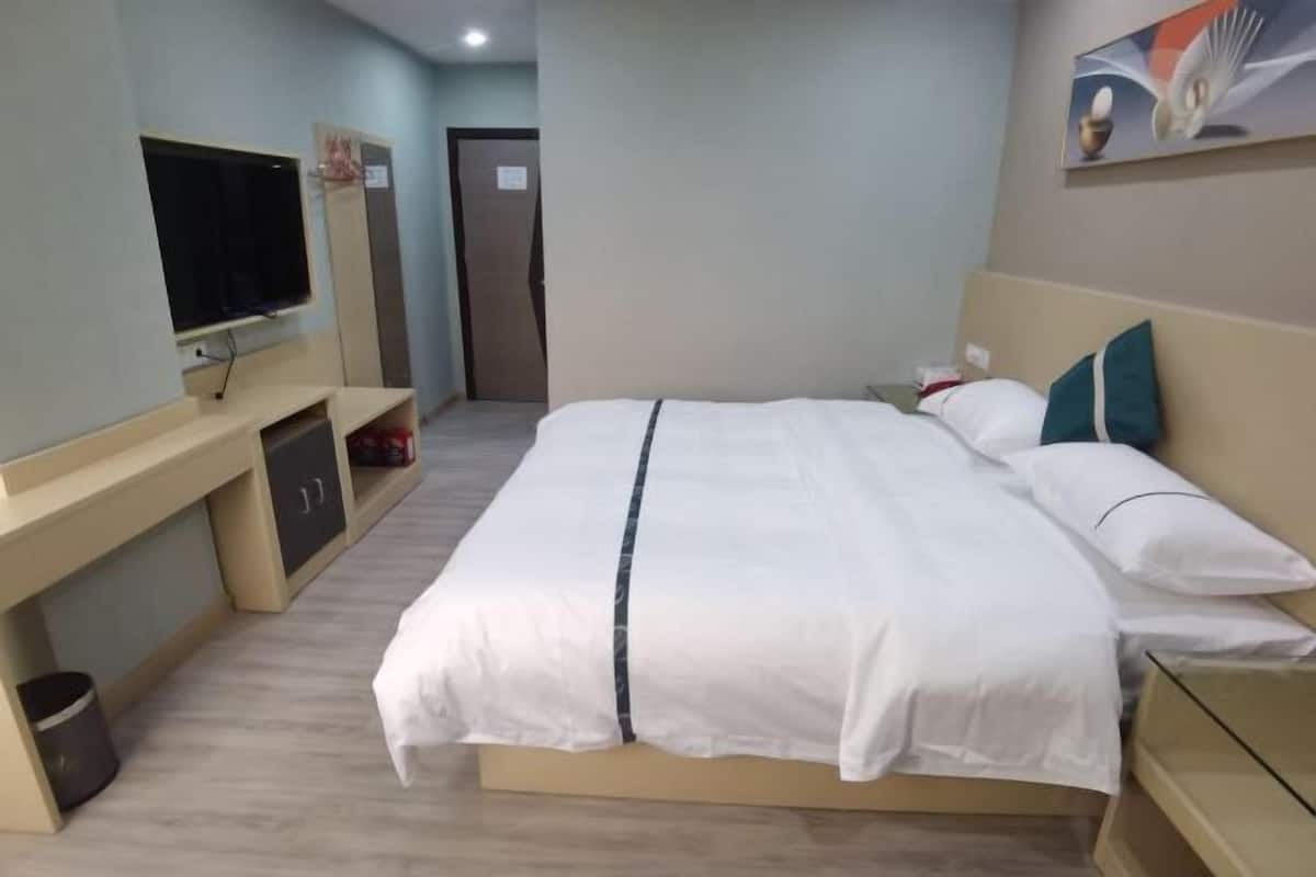 Quarto de hotel com cama, televisão, escrivaninha e porta.