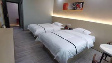 Quarto de hotel com duas camas, uma mesinha e um quadro na parede.